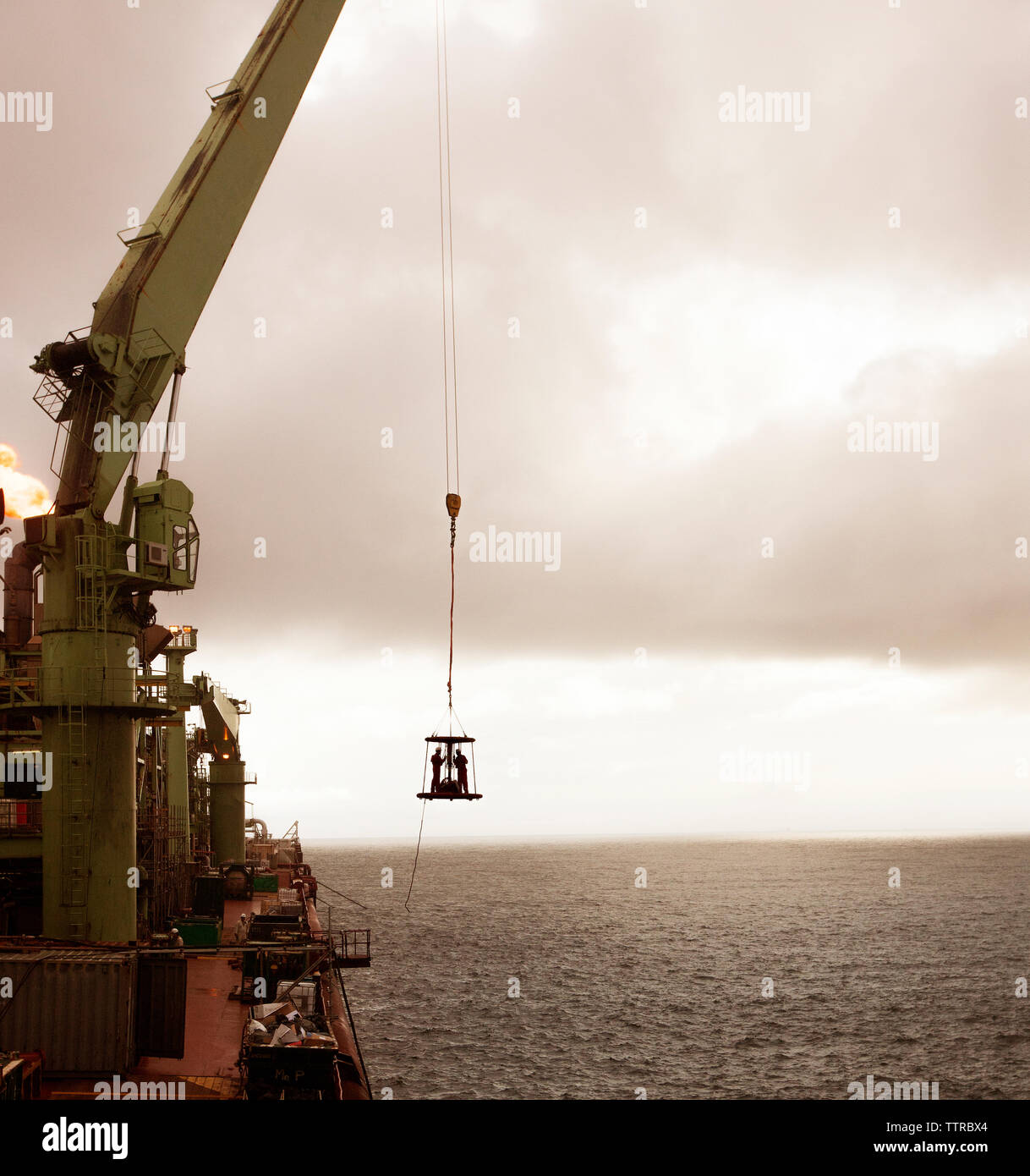 workers on platform hanging by crane over sea Stock Photo - Alamy