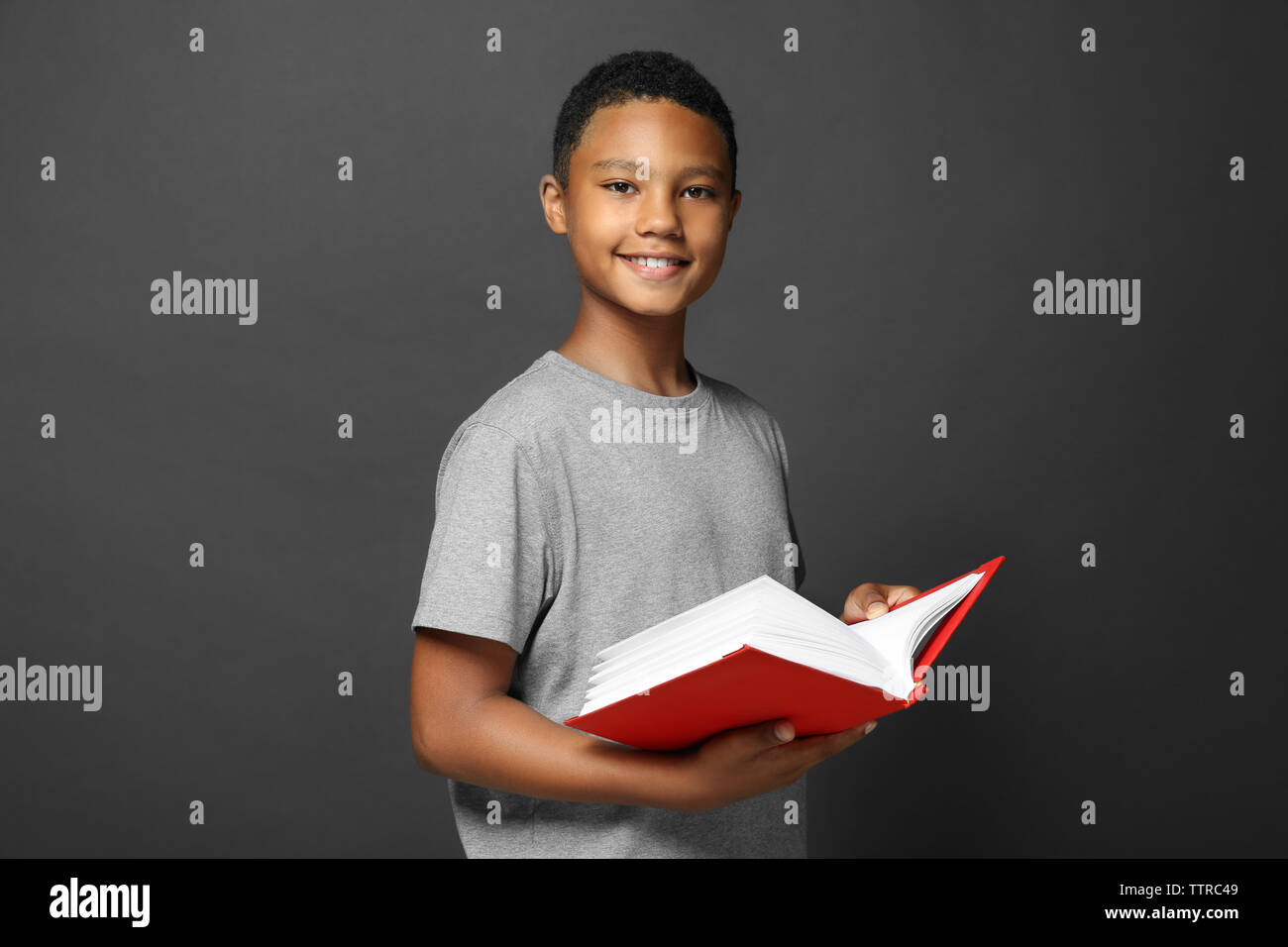 Cute boy reading book on grey background Stock Photo - Alamy
