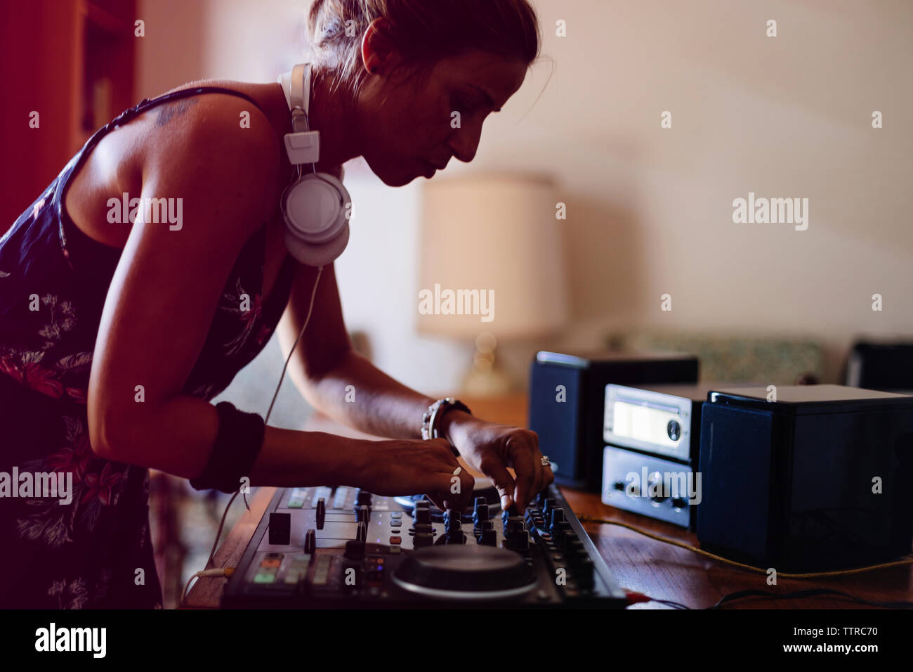 Side view of female DJ mixing sound while standing in recording studio ...