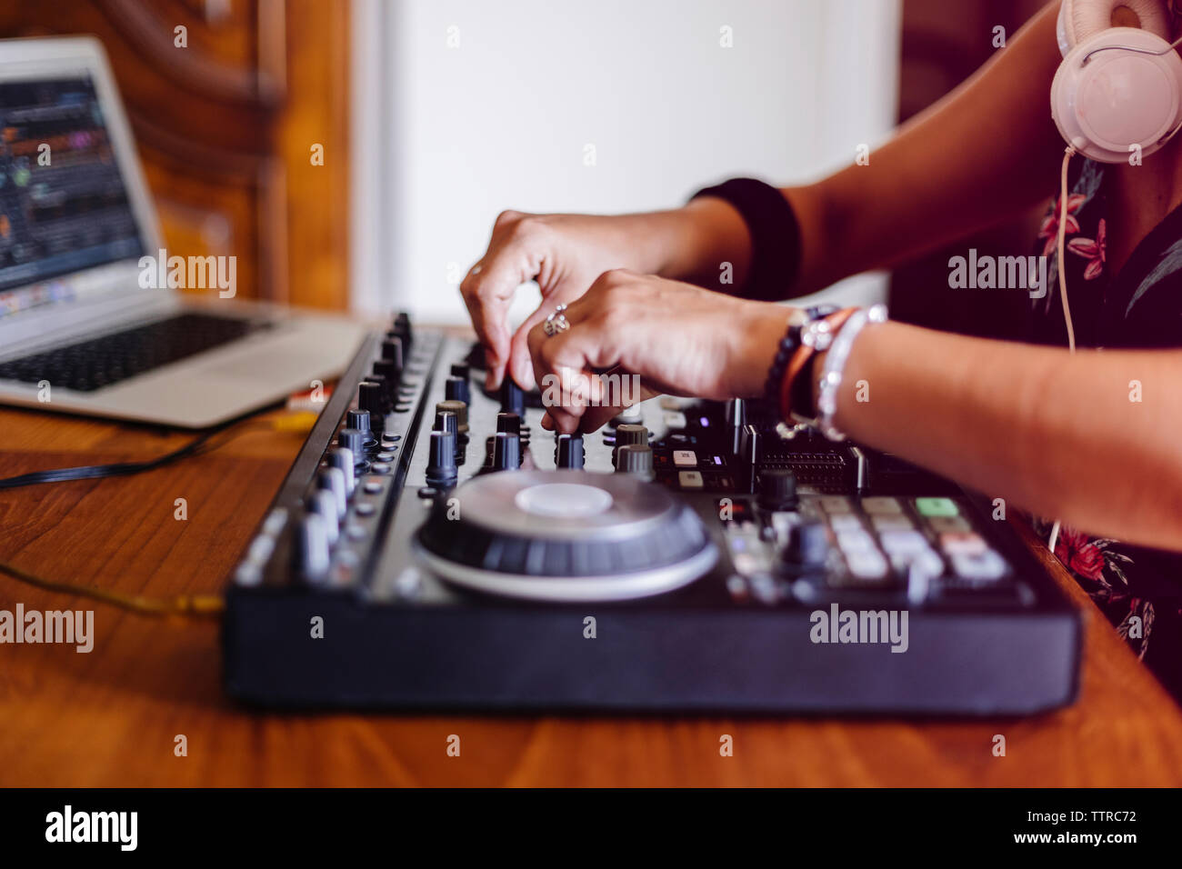 Midsection of female DJ using laptop computer while mixing sound in ...