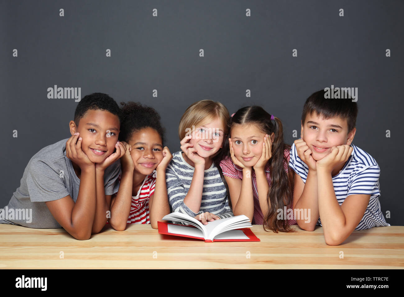 Cute kids reading book on grey background Stock Photo - Alamy