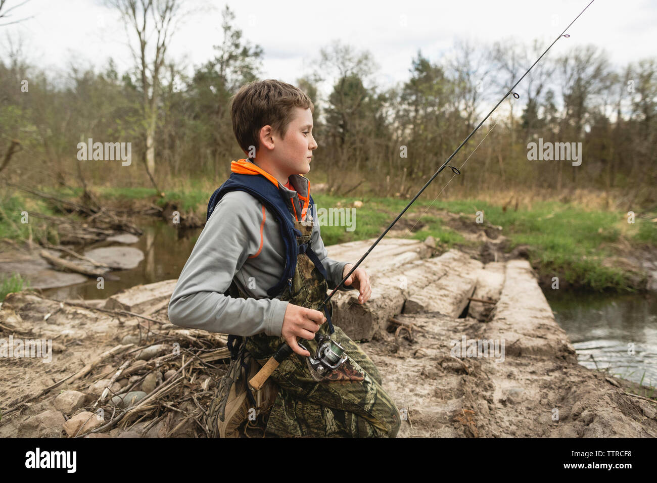 Side view of boy fishing at lakeshore in forest Stock Photo - Alamy
