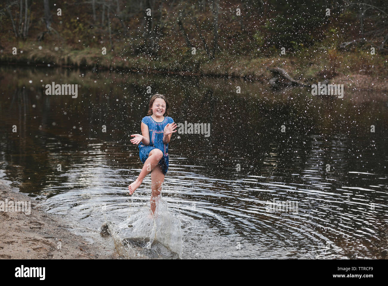 Cute girl playing in lake at forest Stock Photo - Alamy