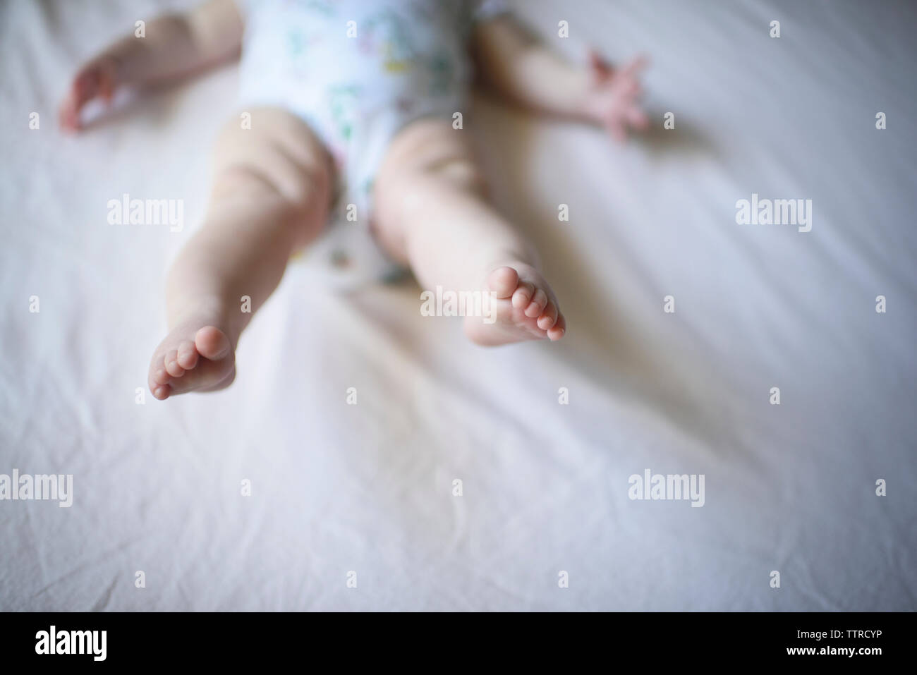 Low section of baby girl lying in crib at home Stock Photo - Alamy