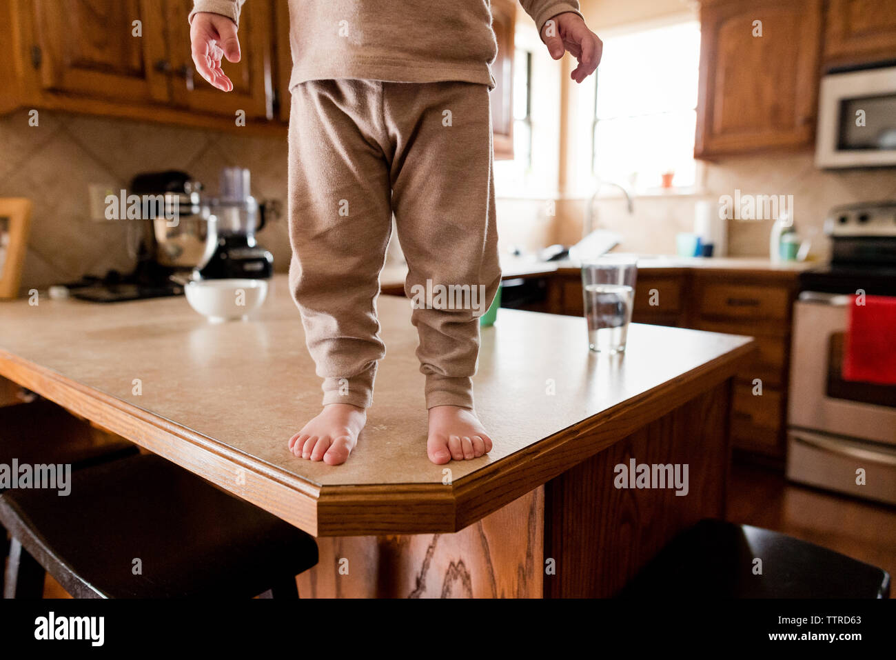 Low section of boy standing on wooden table in kitchen Stock Photo - Alamy