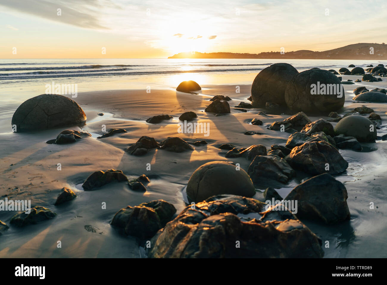 Rocks at beach against sky during sunset Stock Photo - Alamy
