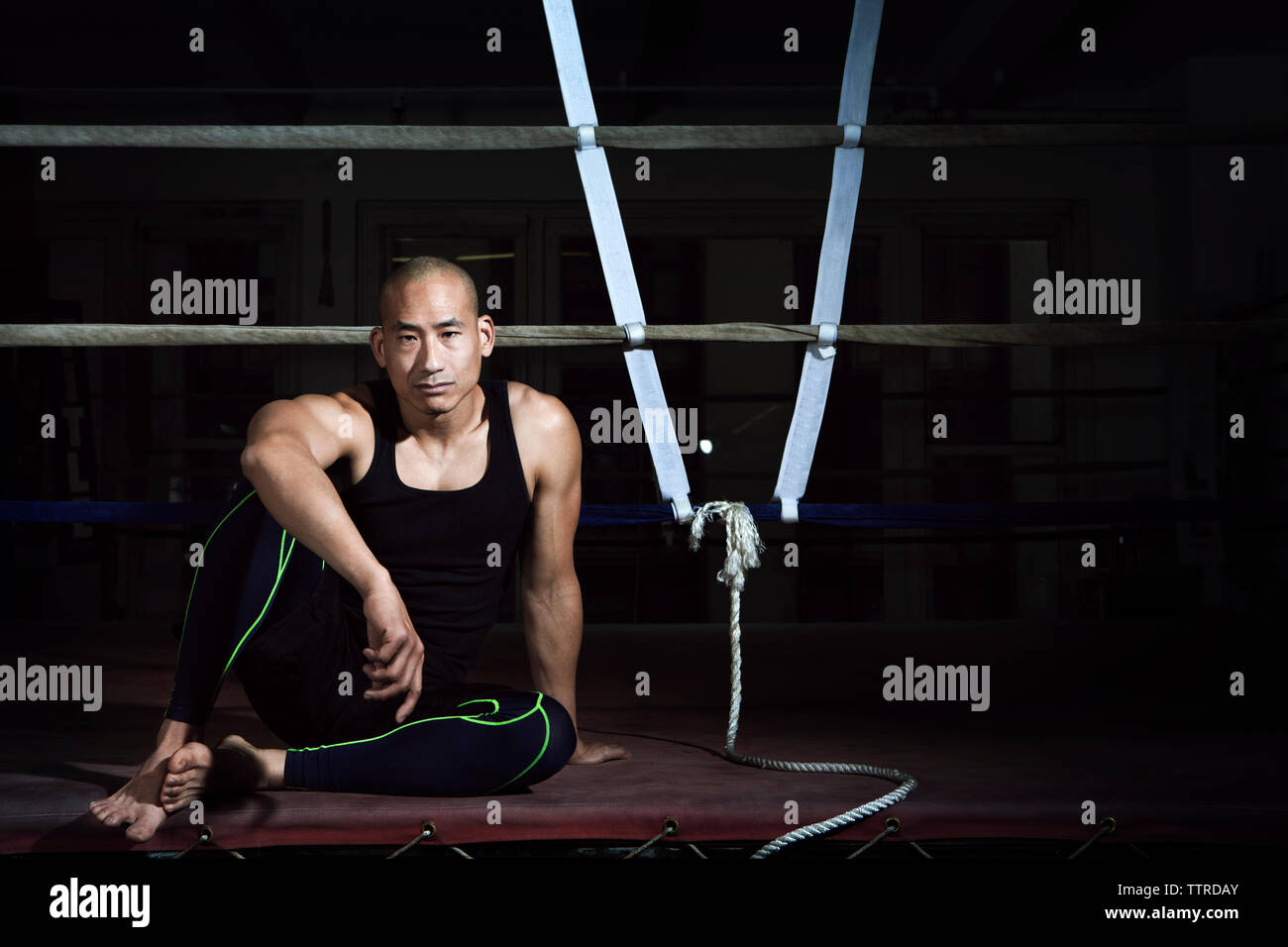 Confident athlete sitting on bench against boxing ring in gym Stock ...