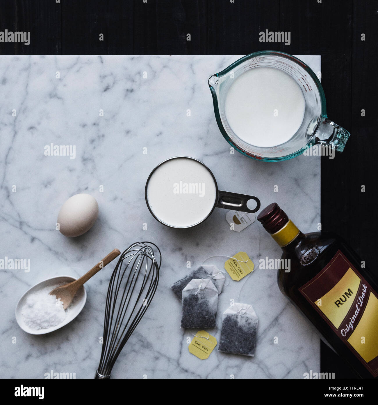 Overhead view of milk and alcohol with egg on table against black ...