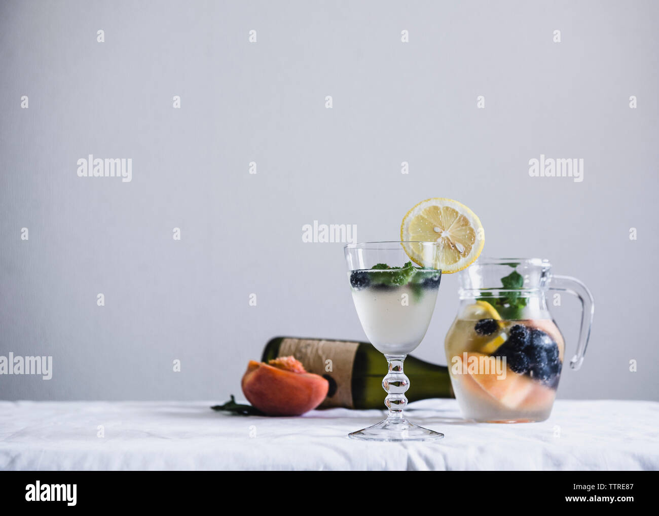 Cold drinks in glass and jug on table against white wall Stock Photo ...