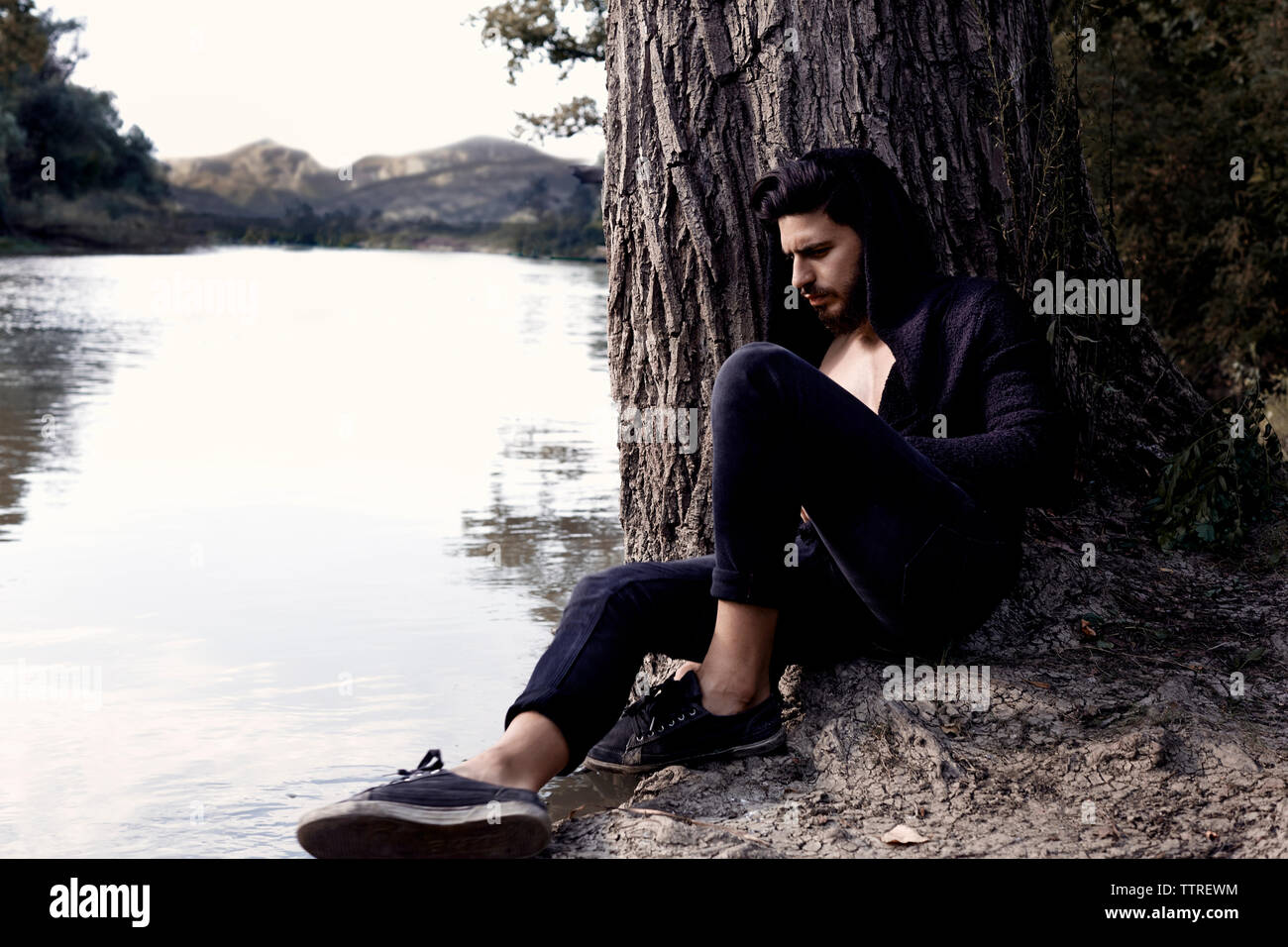 Man sitting against tree trunk hi-res stock photography and images - Alamy