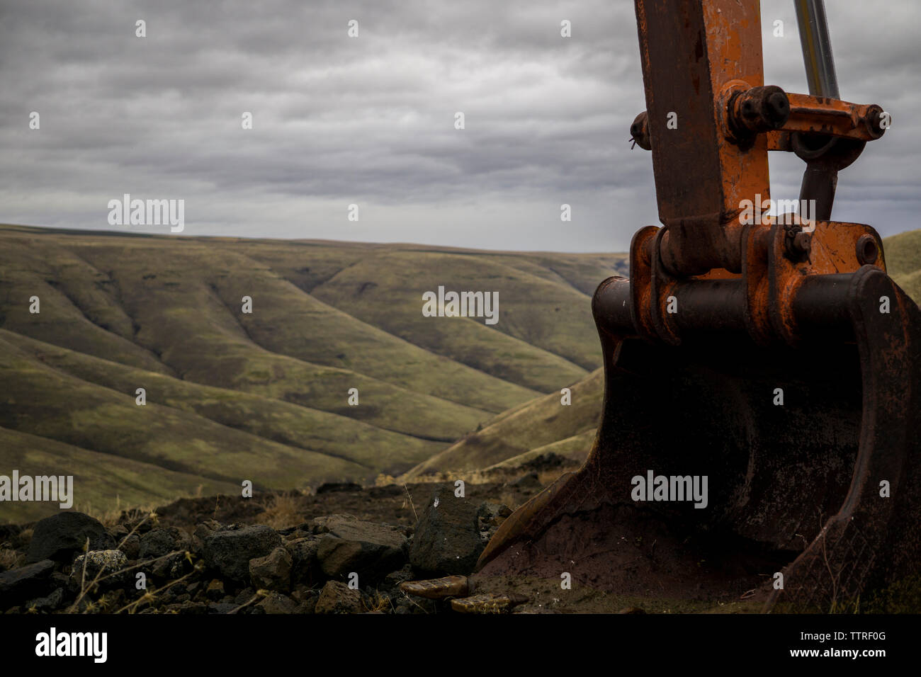 Excavator digging mountain against cloudy sky Stock Photo - Alamy