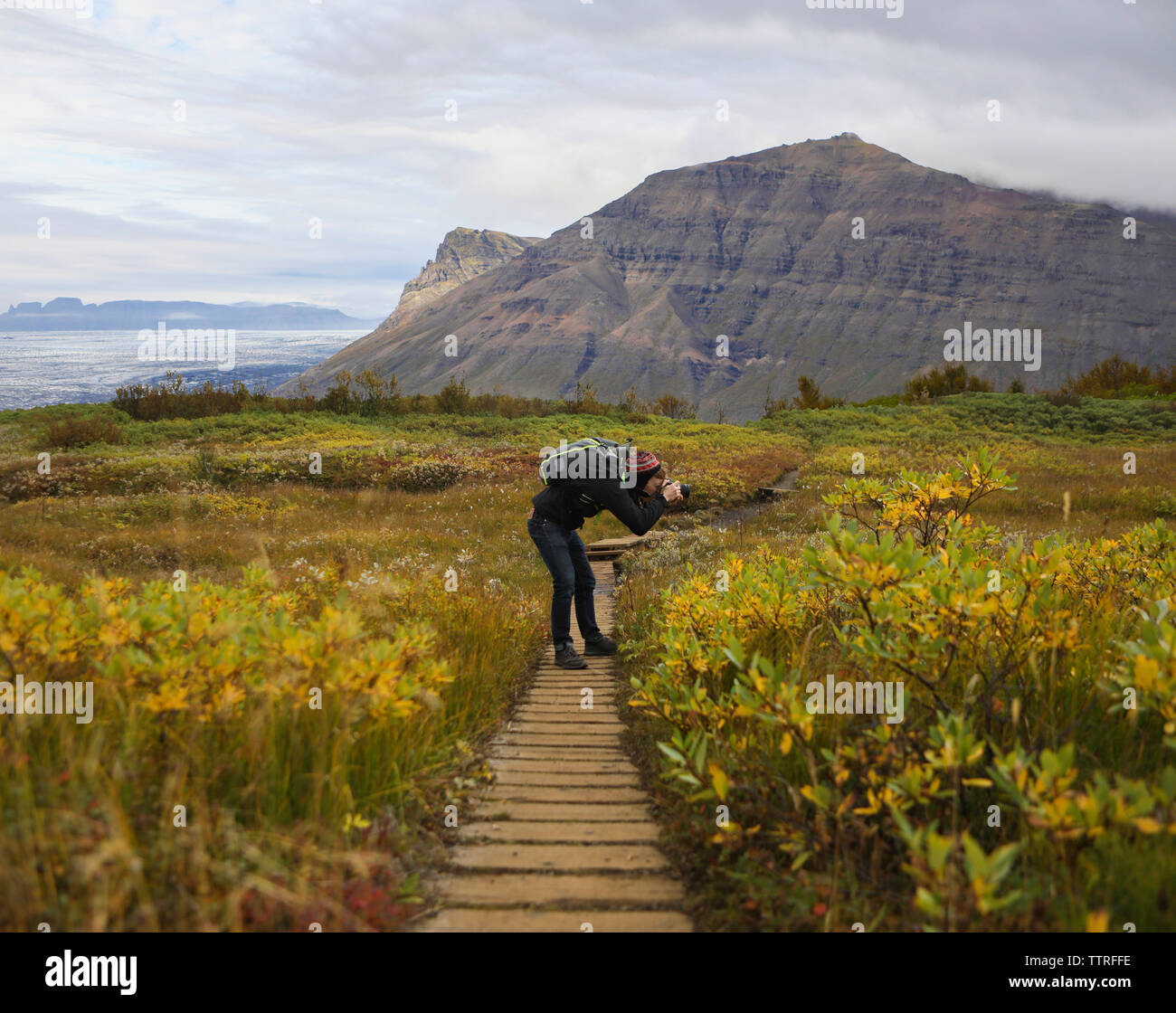 Side view of hiker with backpack photographing with camera while ...