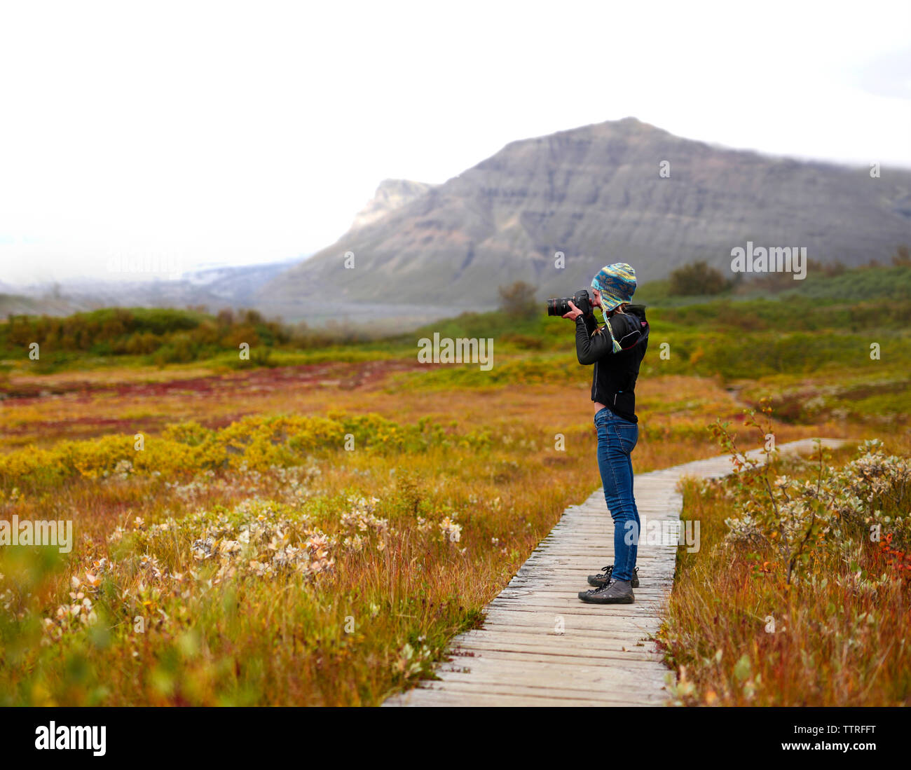 Side view of hiker photographing with camera while standing on ...