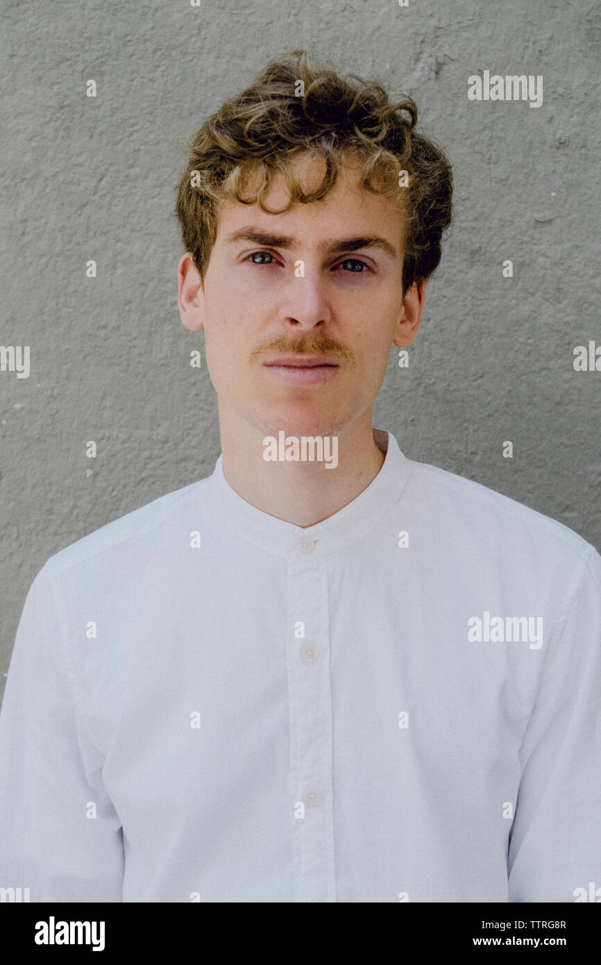 Close-up portrait of confident man standing against concrete wall Stock ...