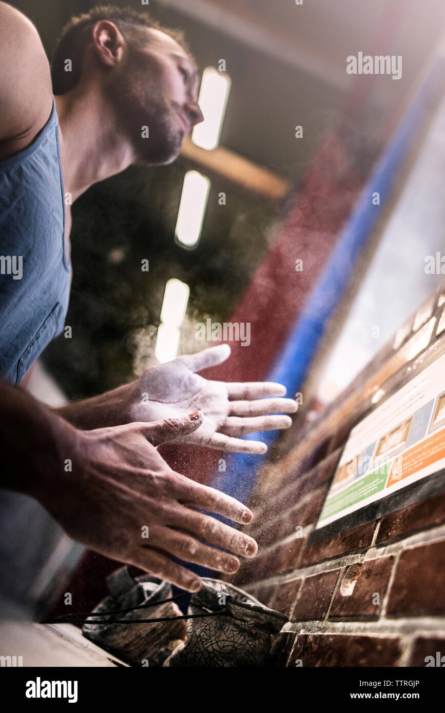 Low angle view of athlete chalking hands while standing in illuminated ...