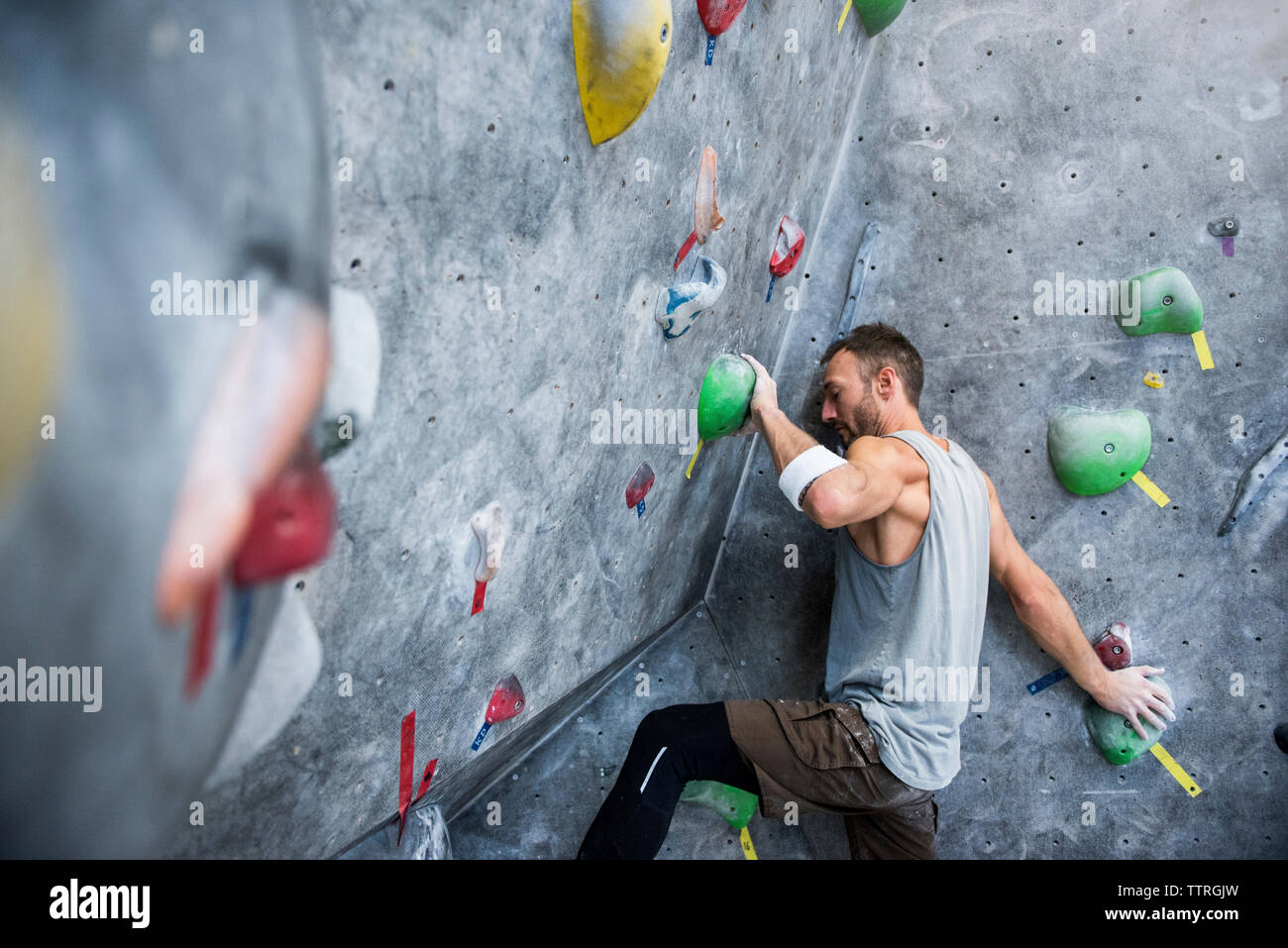 Determined athlete climbing on rock wall at gym Stock Photo - Alamy