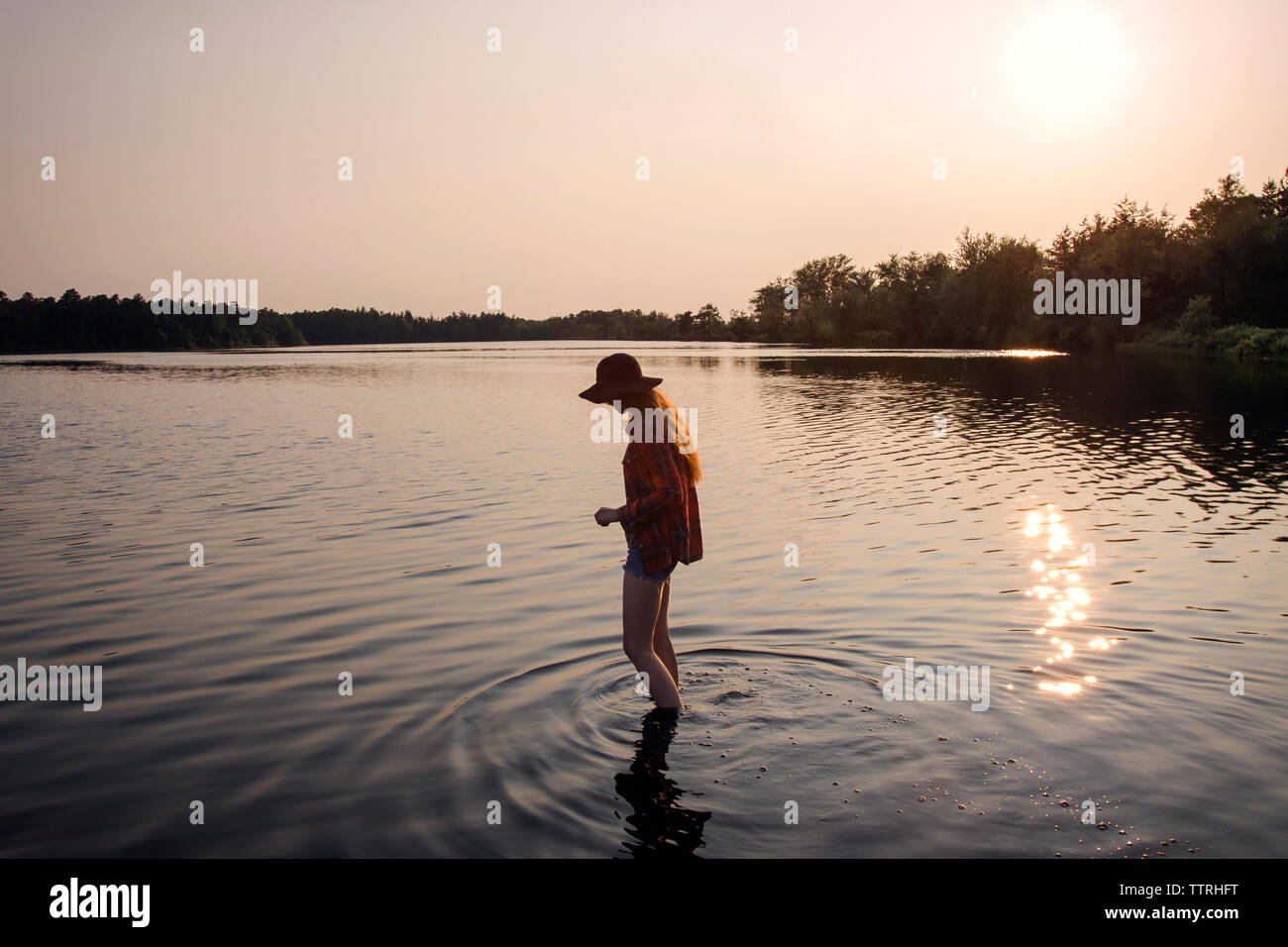 Side view of woman standing in shallow lake water Stock Photo - Alamy