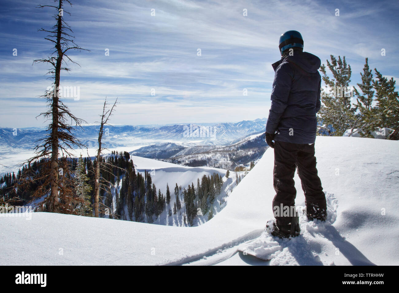 Skier standing on snow covered Wasatch Mountain against cloudy sky ...