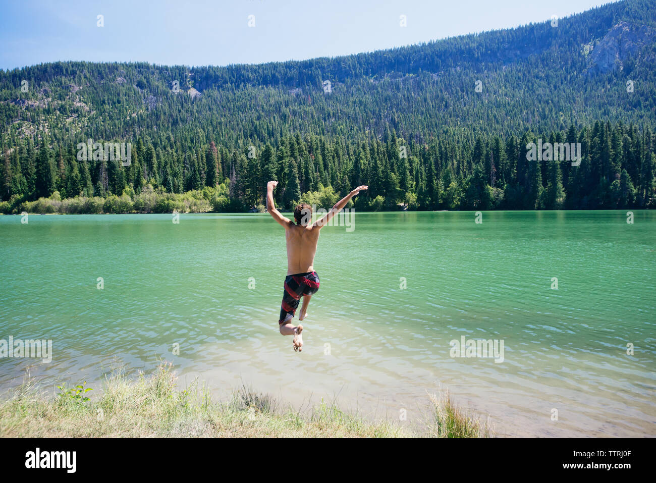 Rear view of man jumping into lake against mountain Stock Photo - Alamy