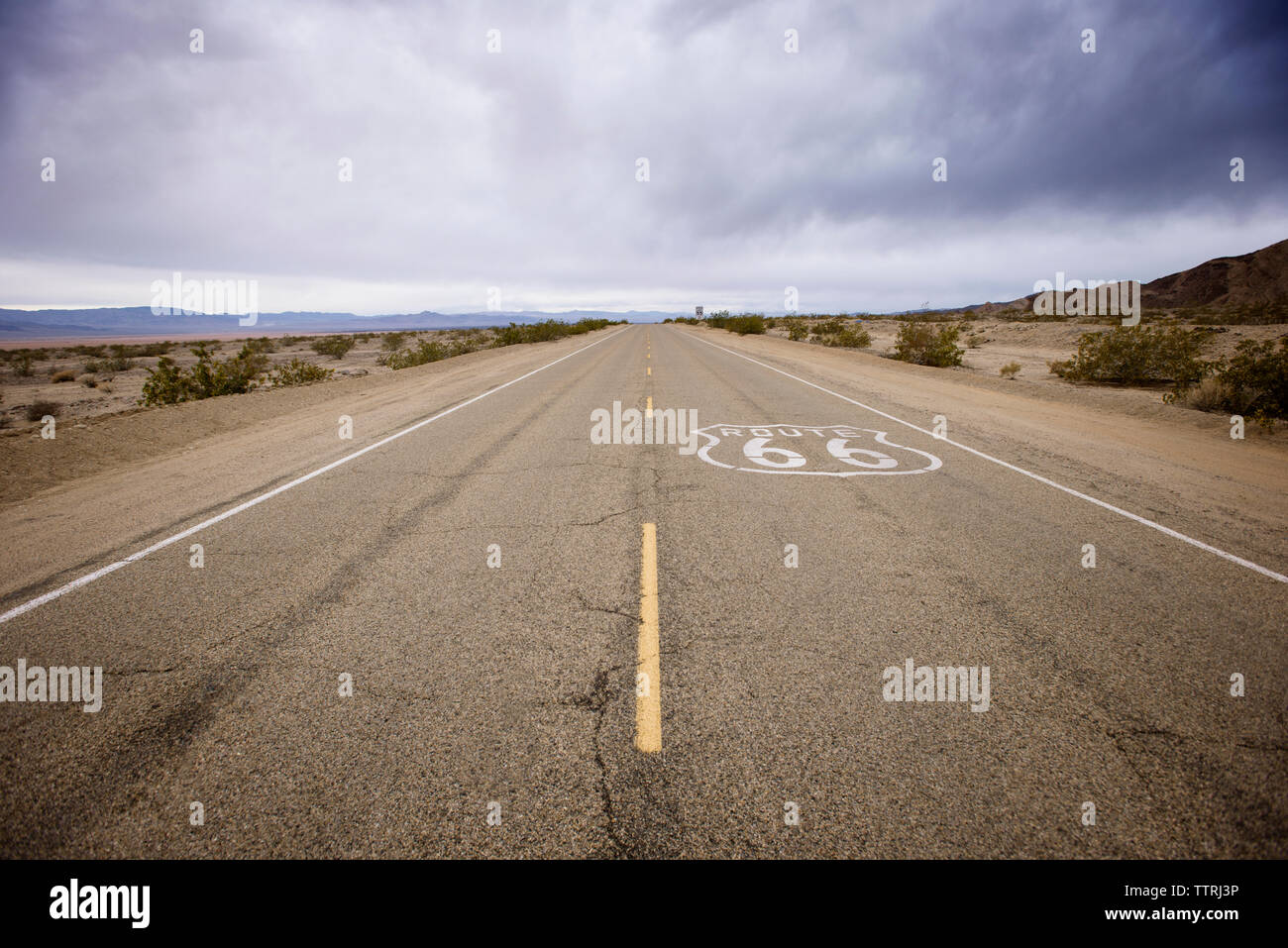 Route 66 sign on desert road against cloudy sky Stock Photo - Alamy