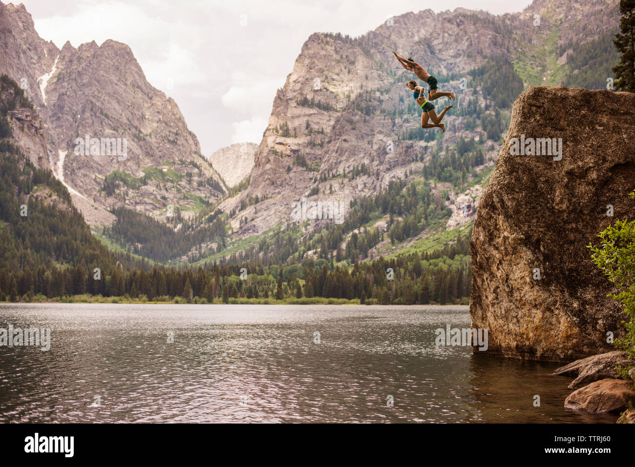Friends diving into lake from cliff at Grand Teton National Park Stock ...