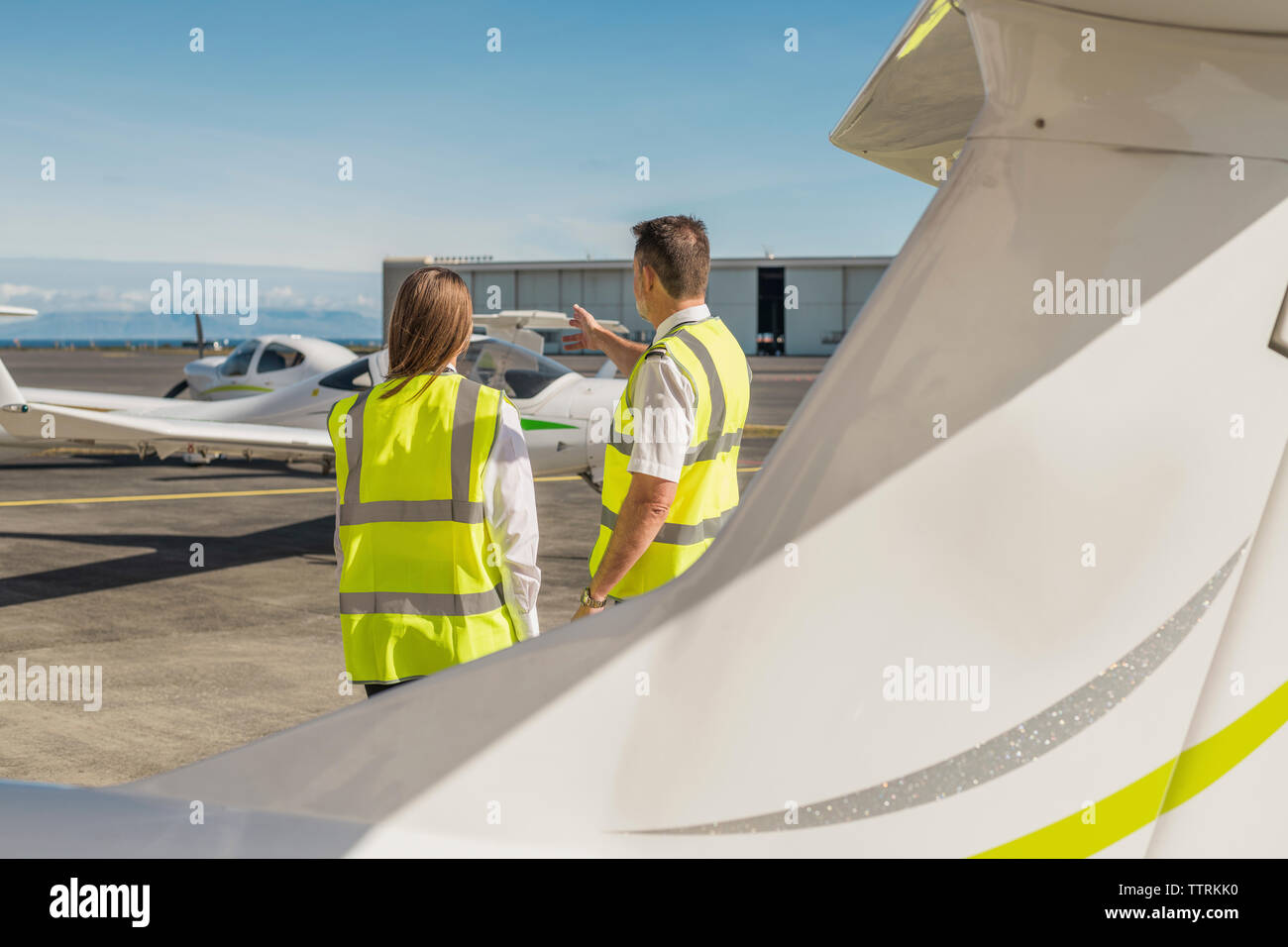 Side view of male engineer guiding female trainee while standing ...
