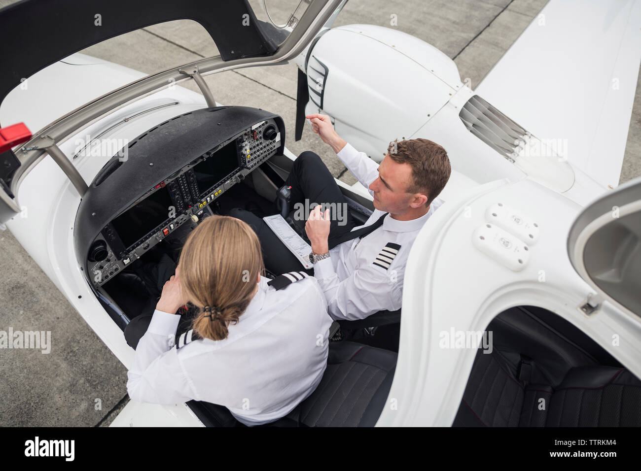 High angle view of male pilot guiding trainee in airplane at airport ...