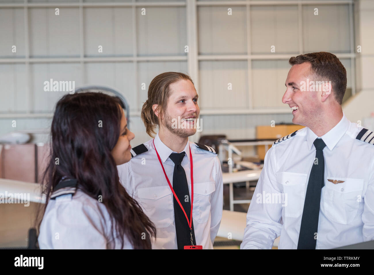 Engineers smiling while standing in airplane hangar Stock Photo - Alamy