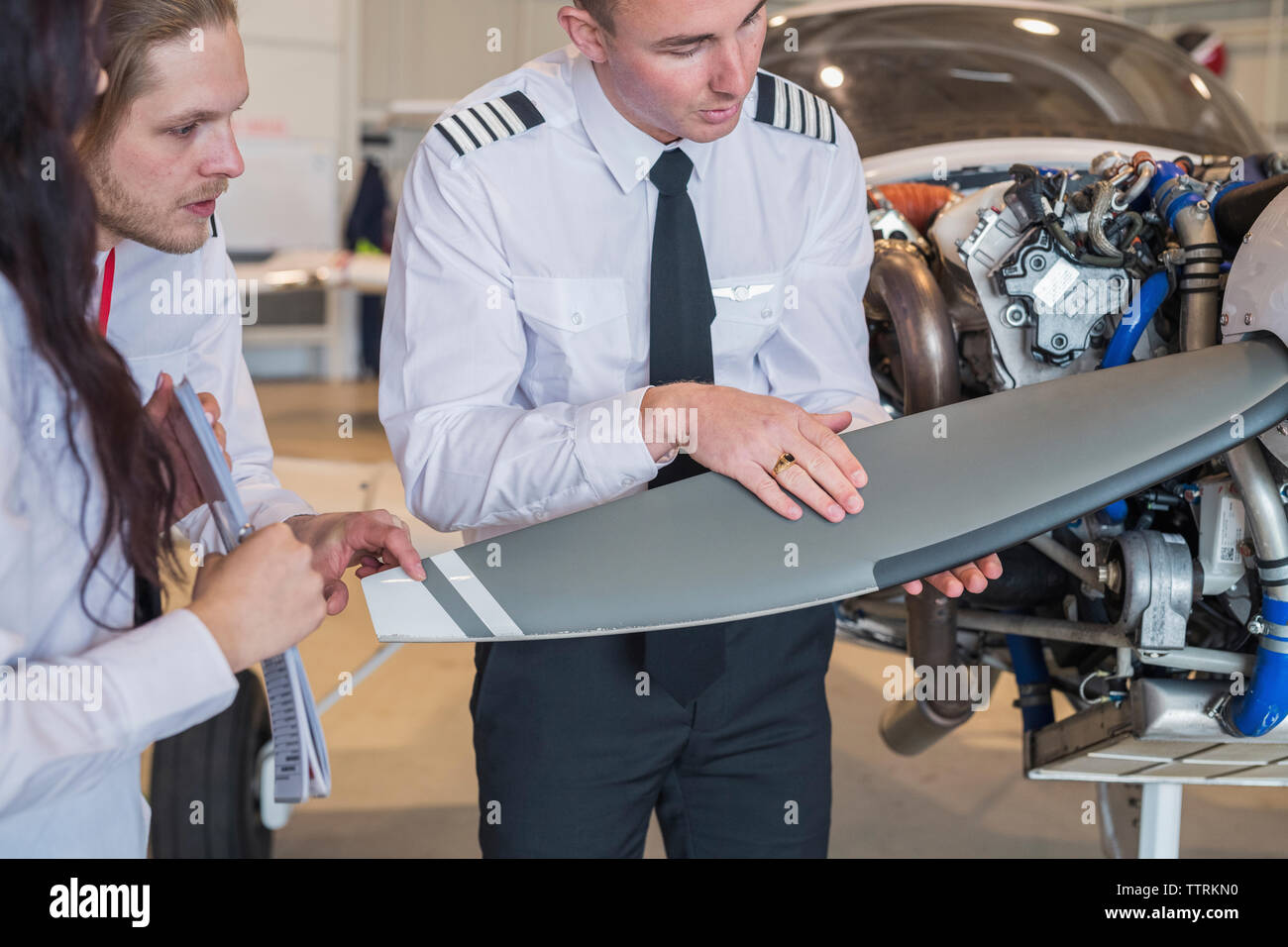 Engineer showing aircraft wing to trainees while standing in hangar ...