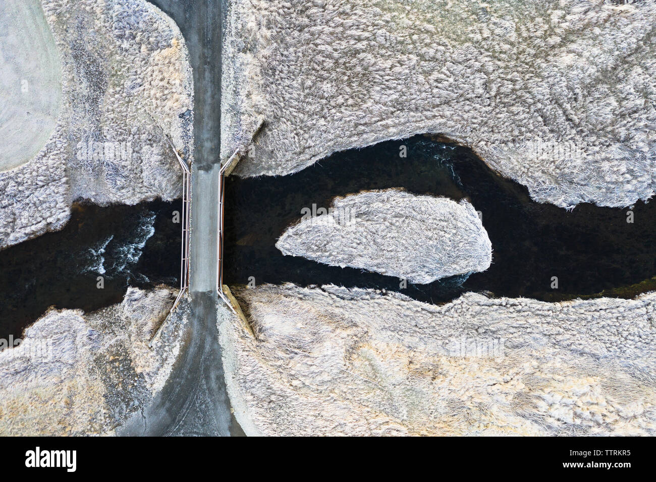 Drone view of asphalt route with bridge above water between wild lands ...