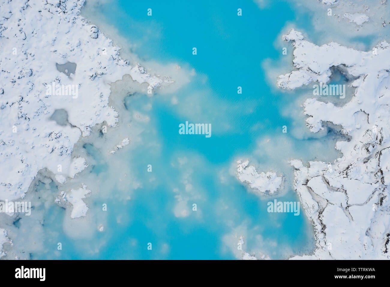 Drone view of amazing blue water of river running between snow lands in ...