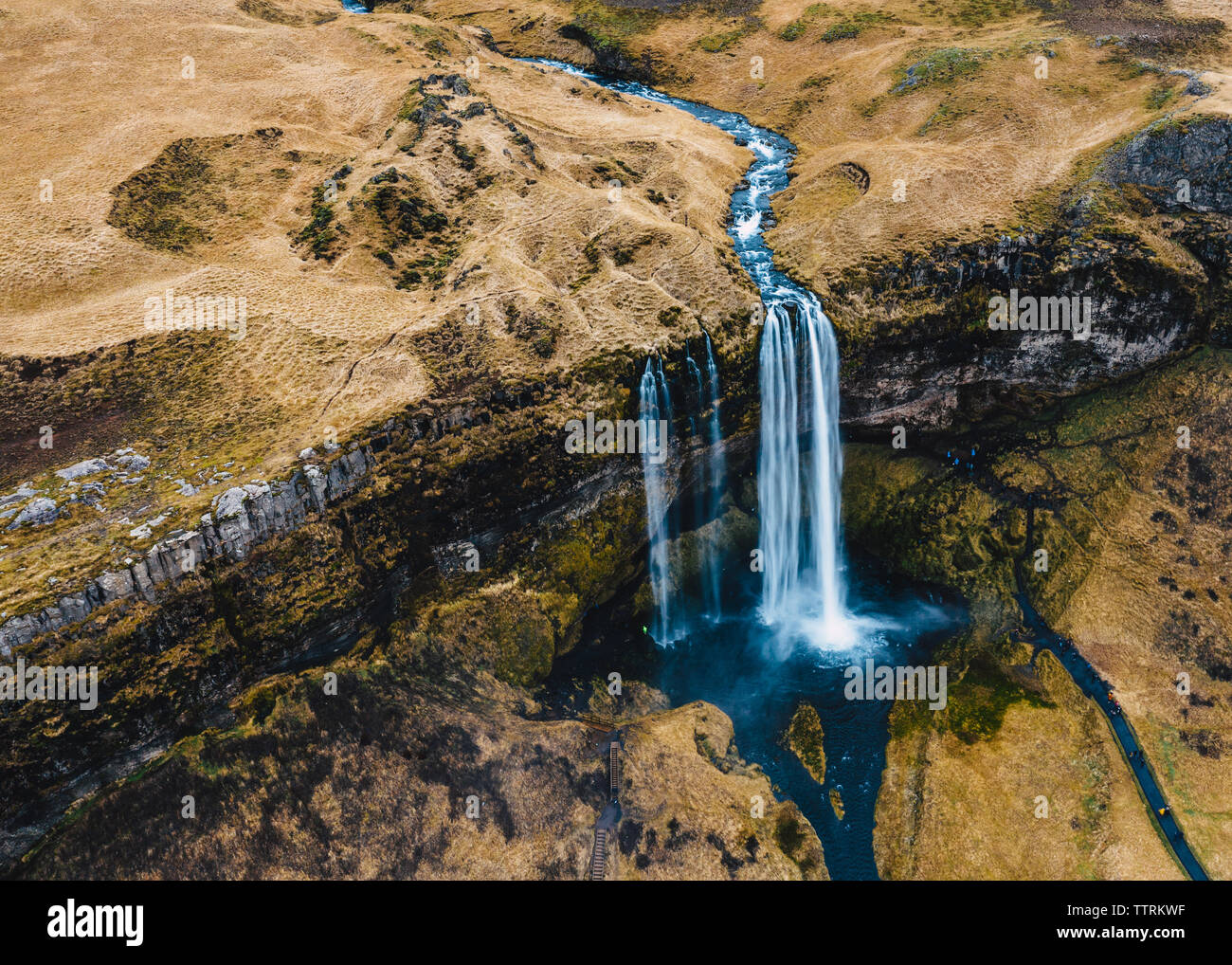 Drone view of narrow river falling from cliff between wild lands Stock ...