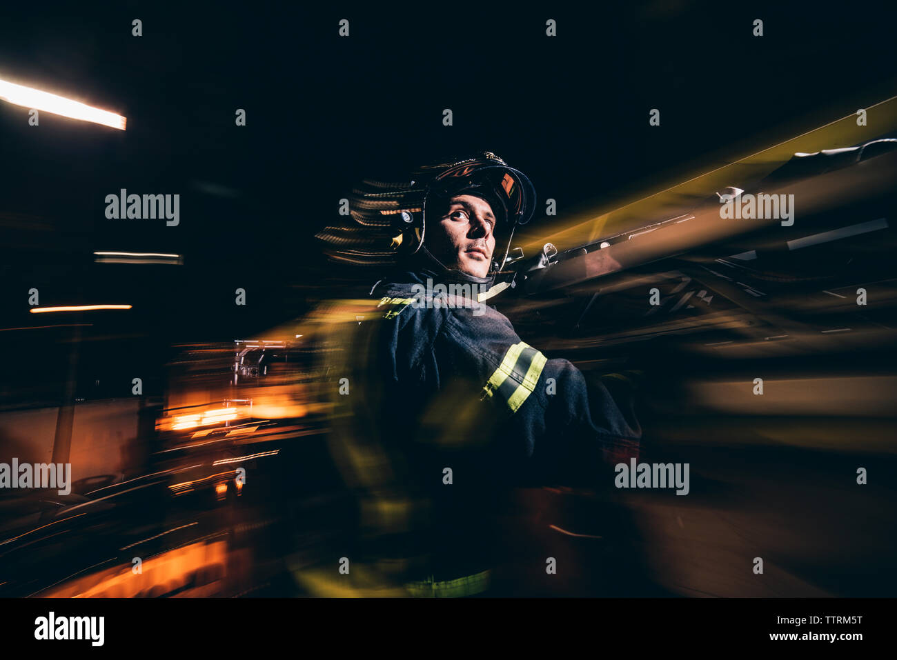 Firefighter riding on outside of fire truck at night Stock Photo - Alamy