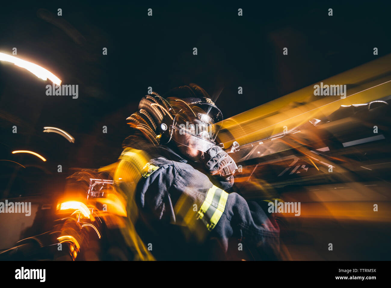 Firefighter riding on outside of fire truck at night Stock Photo - Alamy