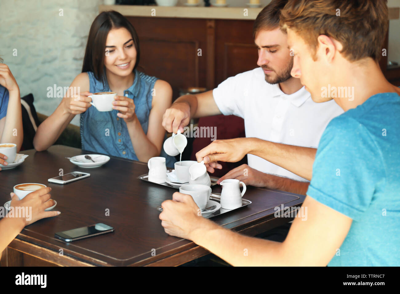Happy friends drinking coffee in cafe Stock Photo - Alamy