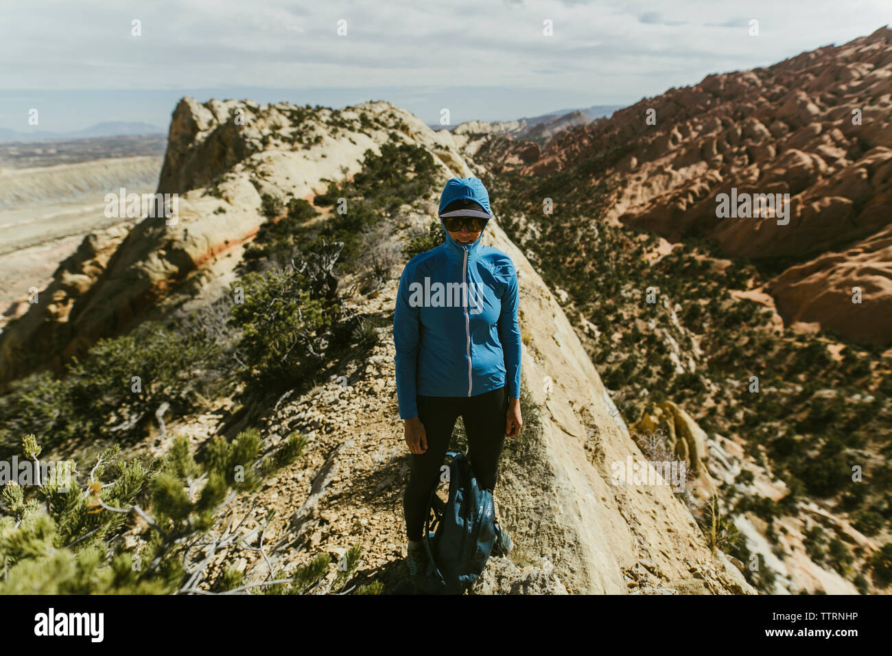 Female hiker with backpack wearing jacket and cap while standing on ...