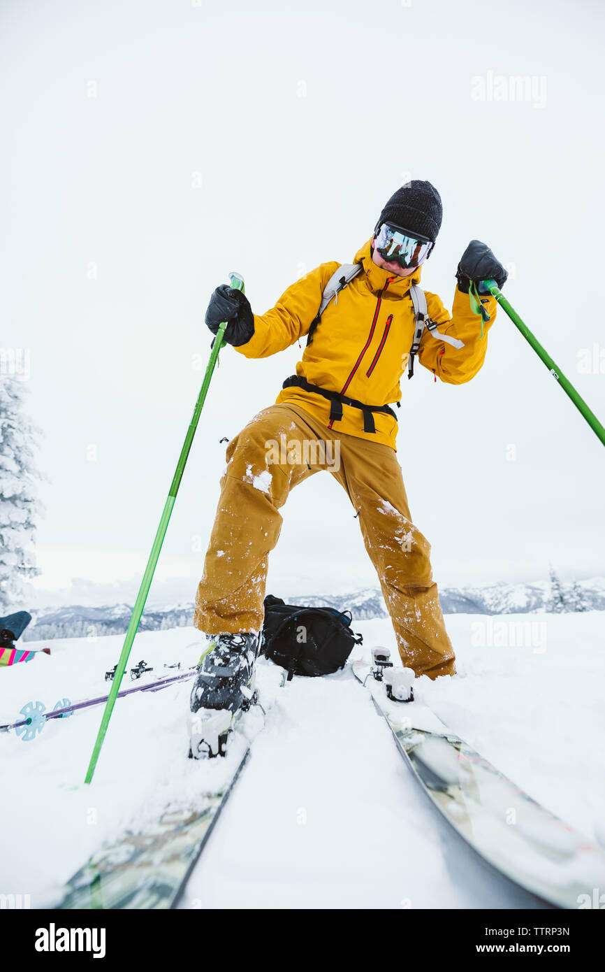 Skier in yellow jacket prepares to ski, puts on skis Stock Photo - Alamy