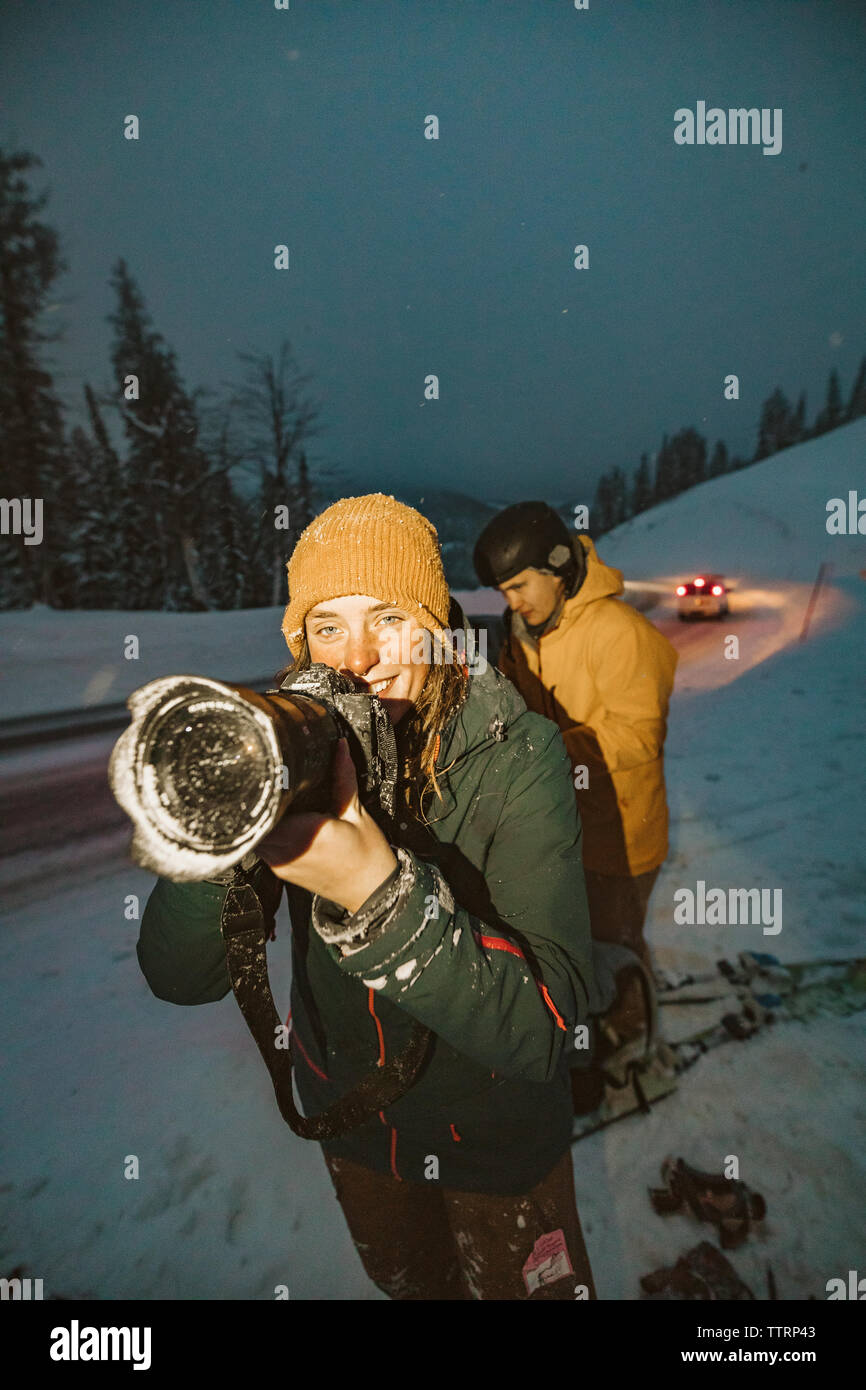 young female photographer smiles and takes a picture with dirty camera ...