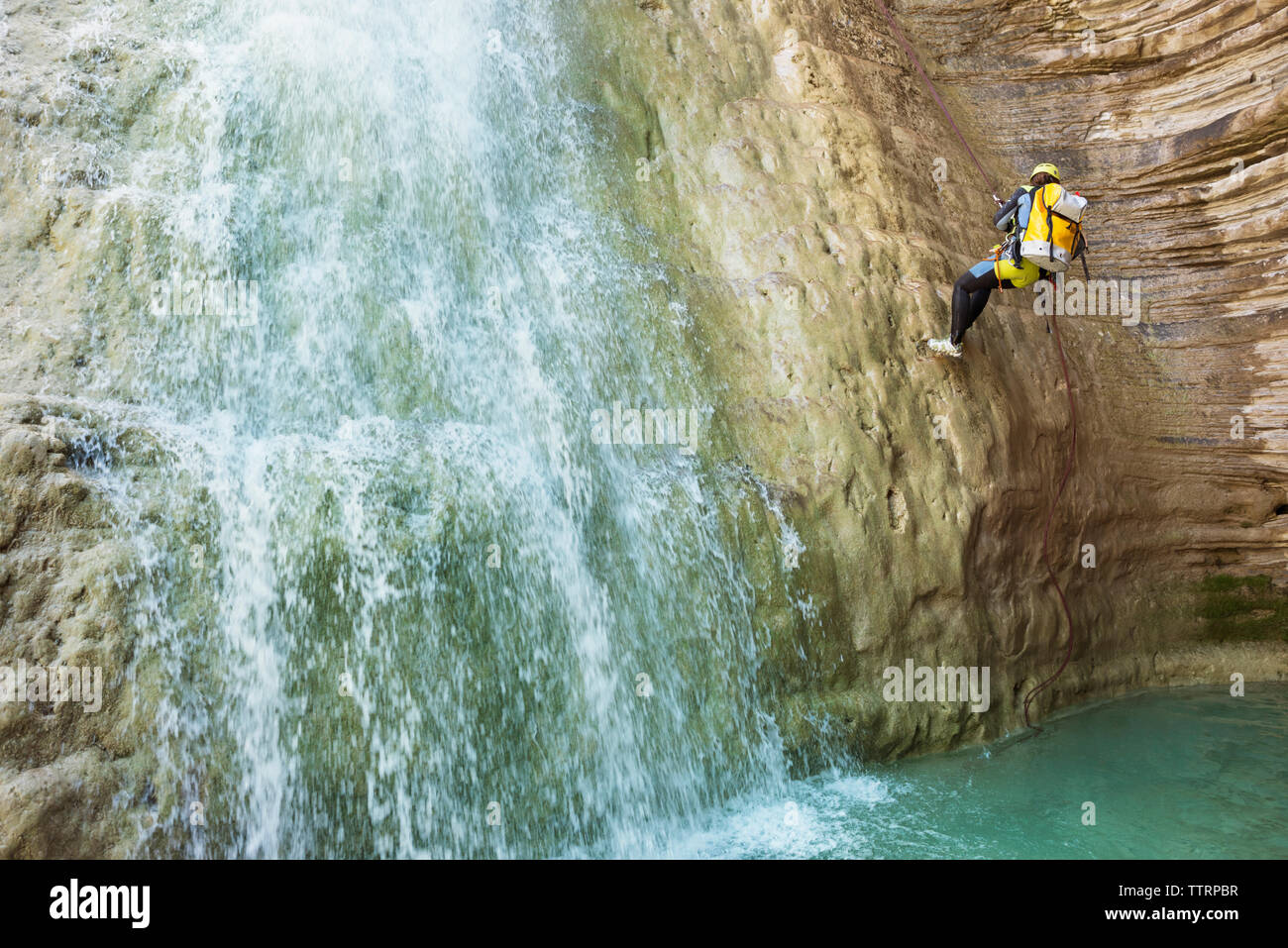 Woman climbing mountain by waterfall Stock Photo - Alamy