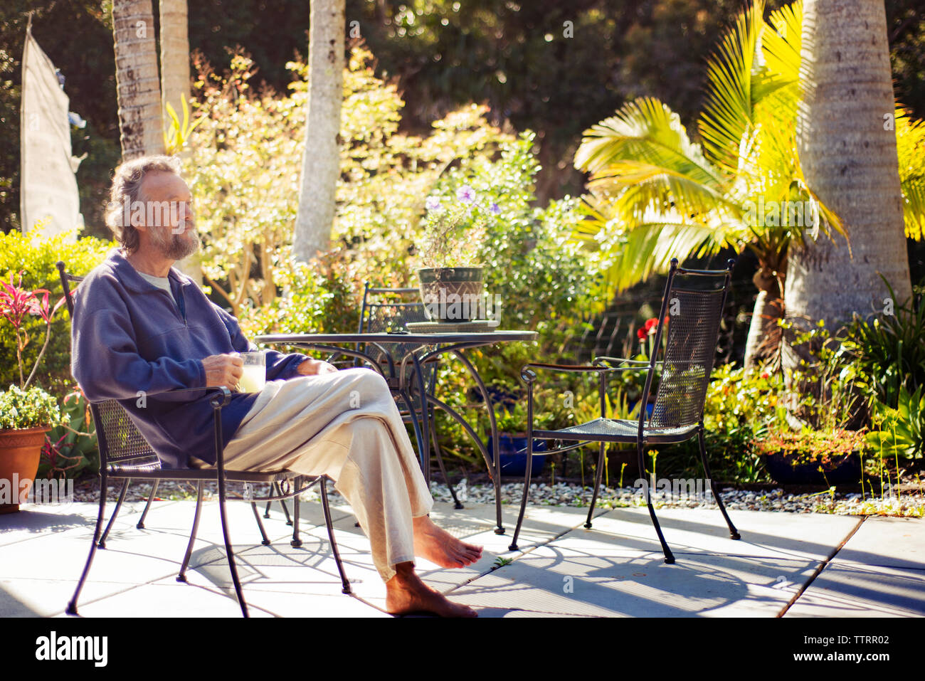 Thoughtful happy senior man sitting on chair in back yard Stock Photo ...