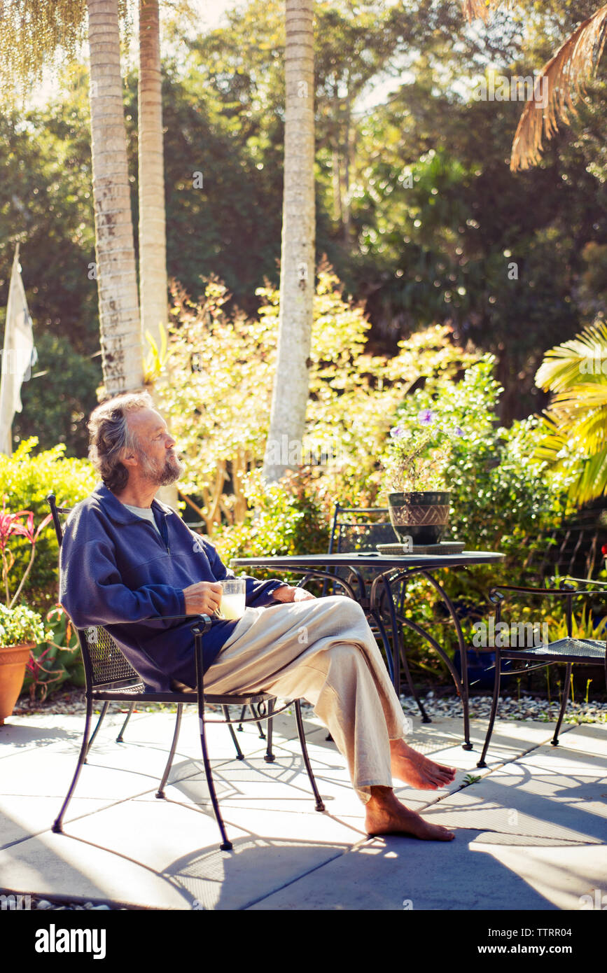 Thoughtful senior man sitting on chair in back yard Stock Photo - Alamy
