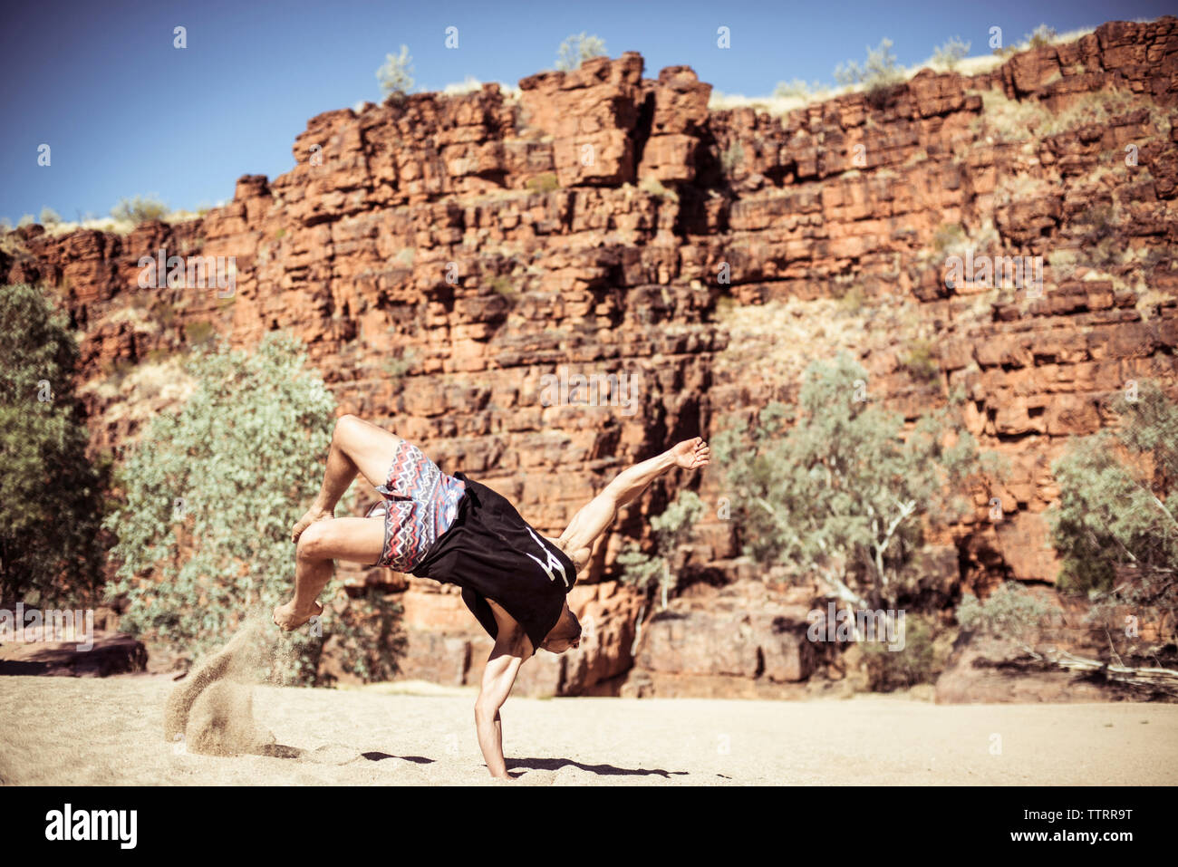 Man dancing on sand against rock formations at desert Stock Photo - Alamy