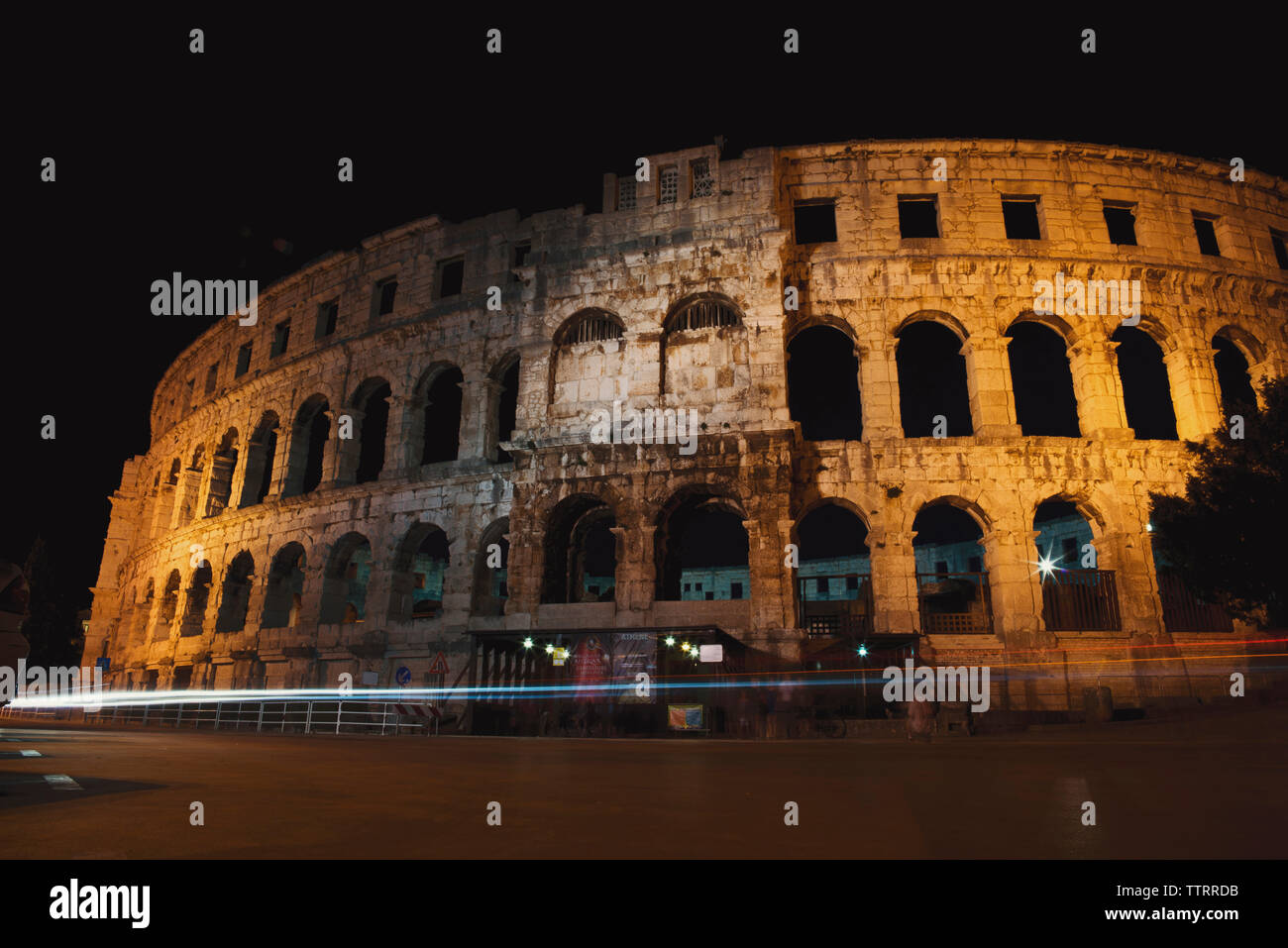 Light trails on road by historic amphitheater against clear sky at ...