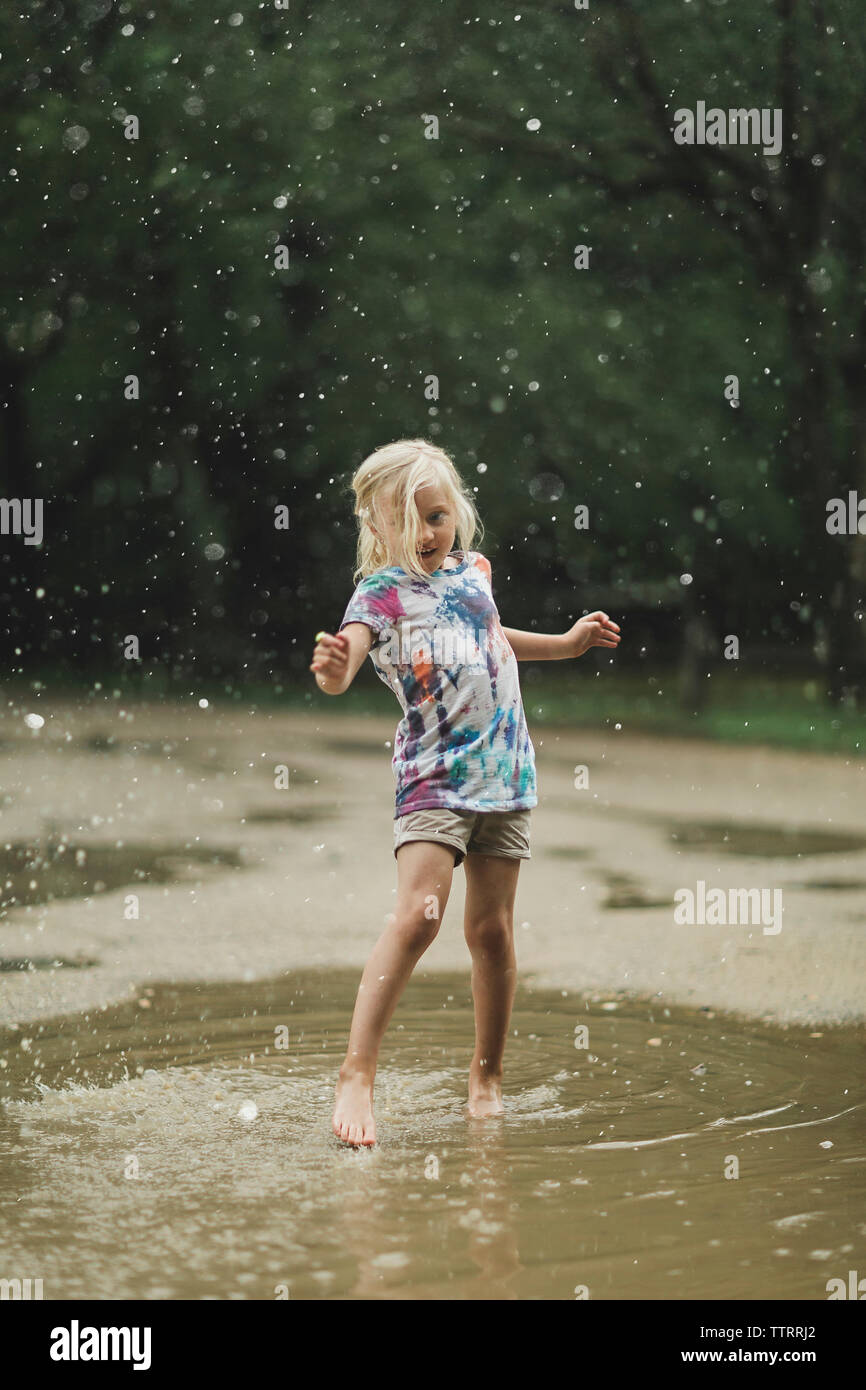 Full length of girl playing in puddle at park Stock Photo - Alamy