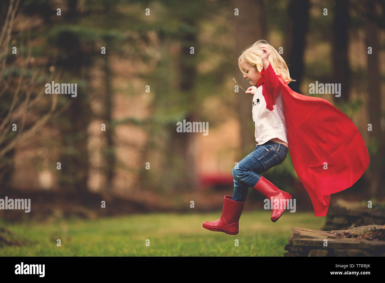 Happy girl wearing cape running against trees at forest Stock Photo - Alamy