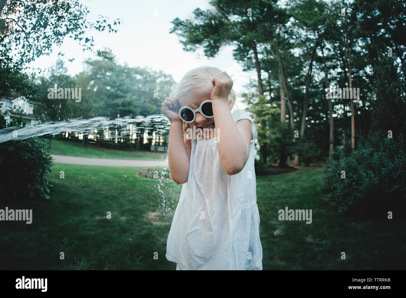 Water splashing over scared girl wearing sunglasses at backyard Stock ...
