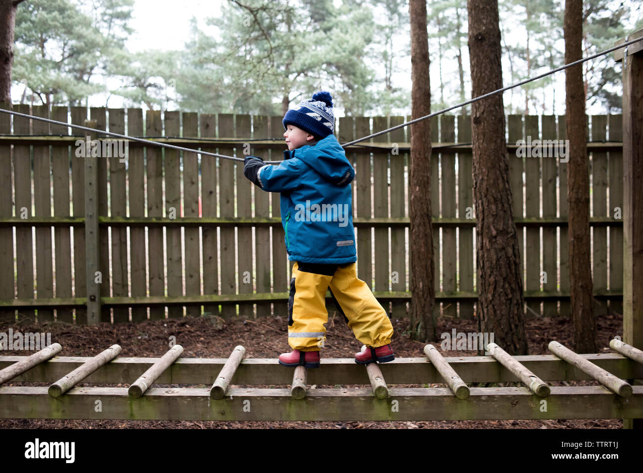 Full length of playful boy walking on jungle gym at playground Stock ...