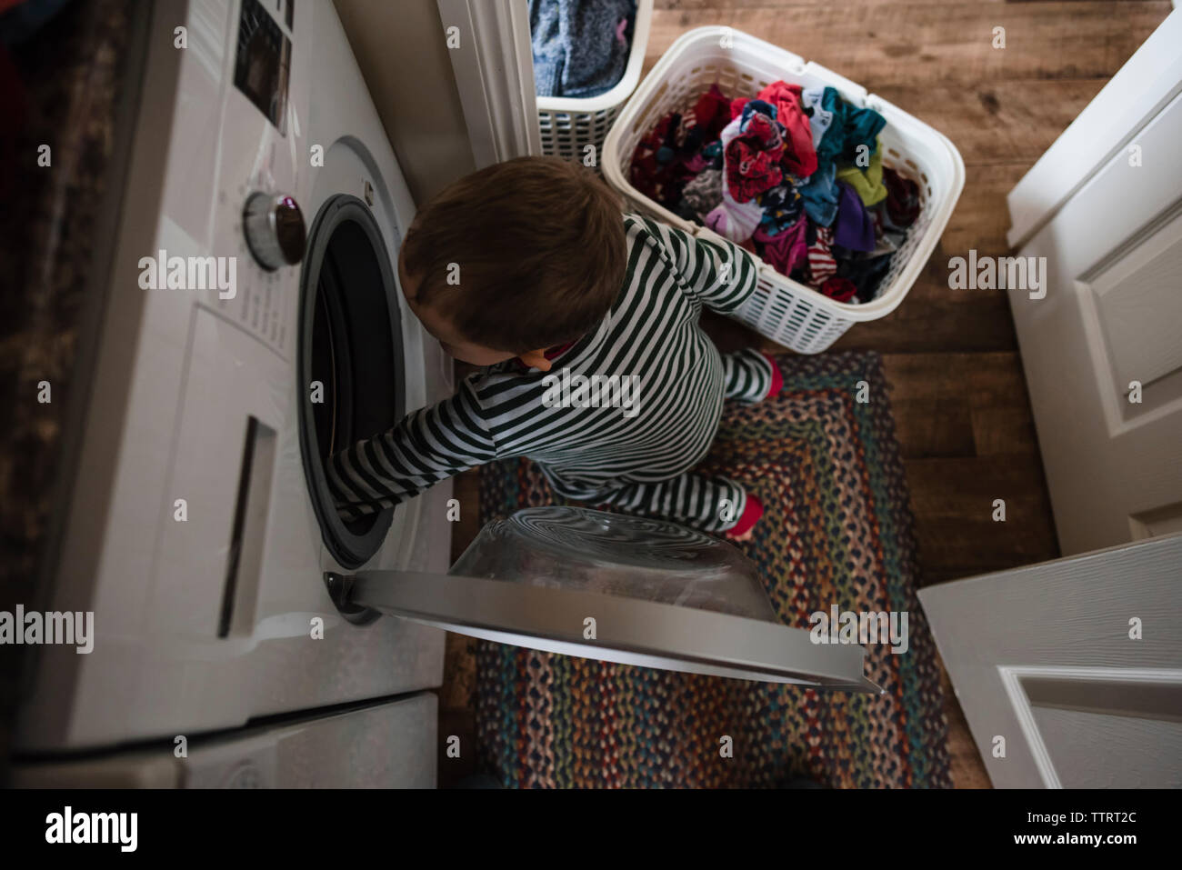 High angle view of boy putting clothes in washing machine at home Stock ...