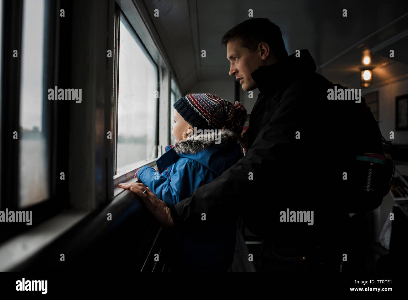 Father and daughter looking through window Stock Photo - Alamy