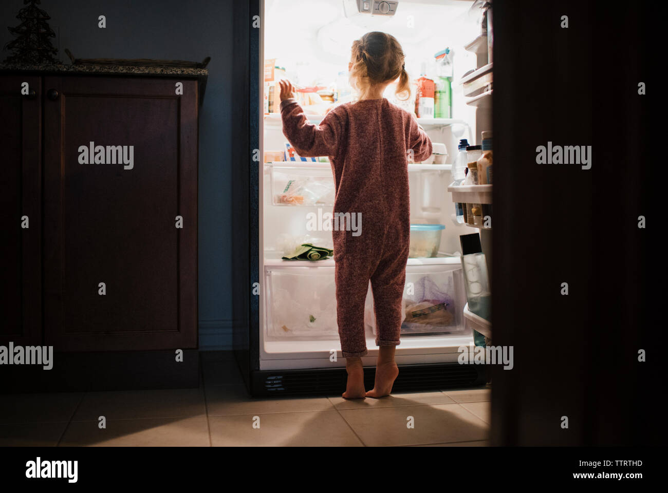 Rear view of girl standing by refrigerator at home Stock Photo - Alamy